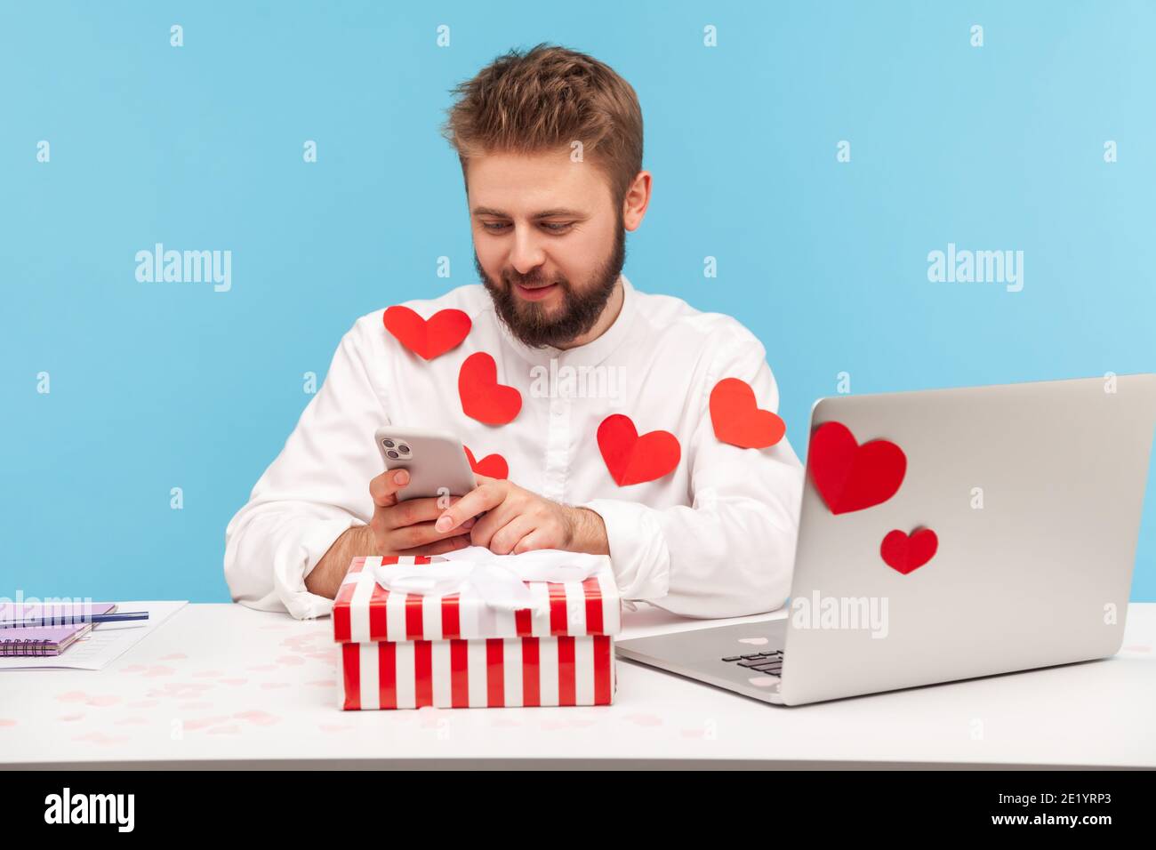 Smiling bearded businessman in white shirt in red heart shaped stickers ...