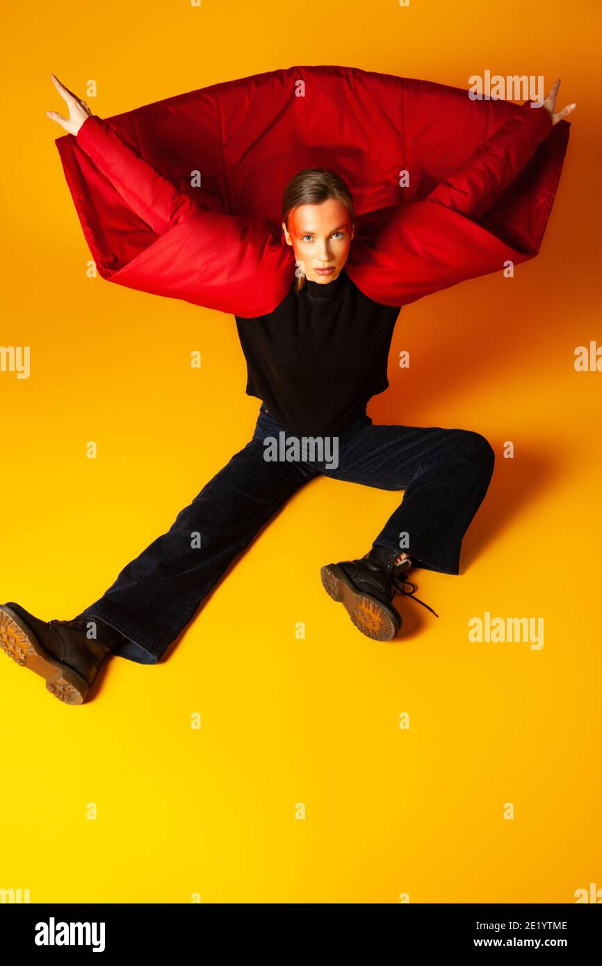 Eccentric female model in warm coat against yellow background Stock ...