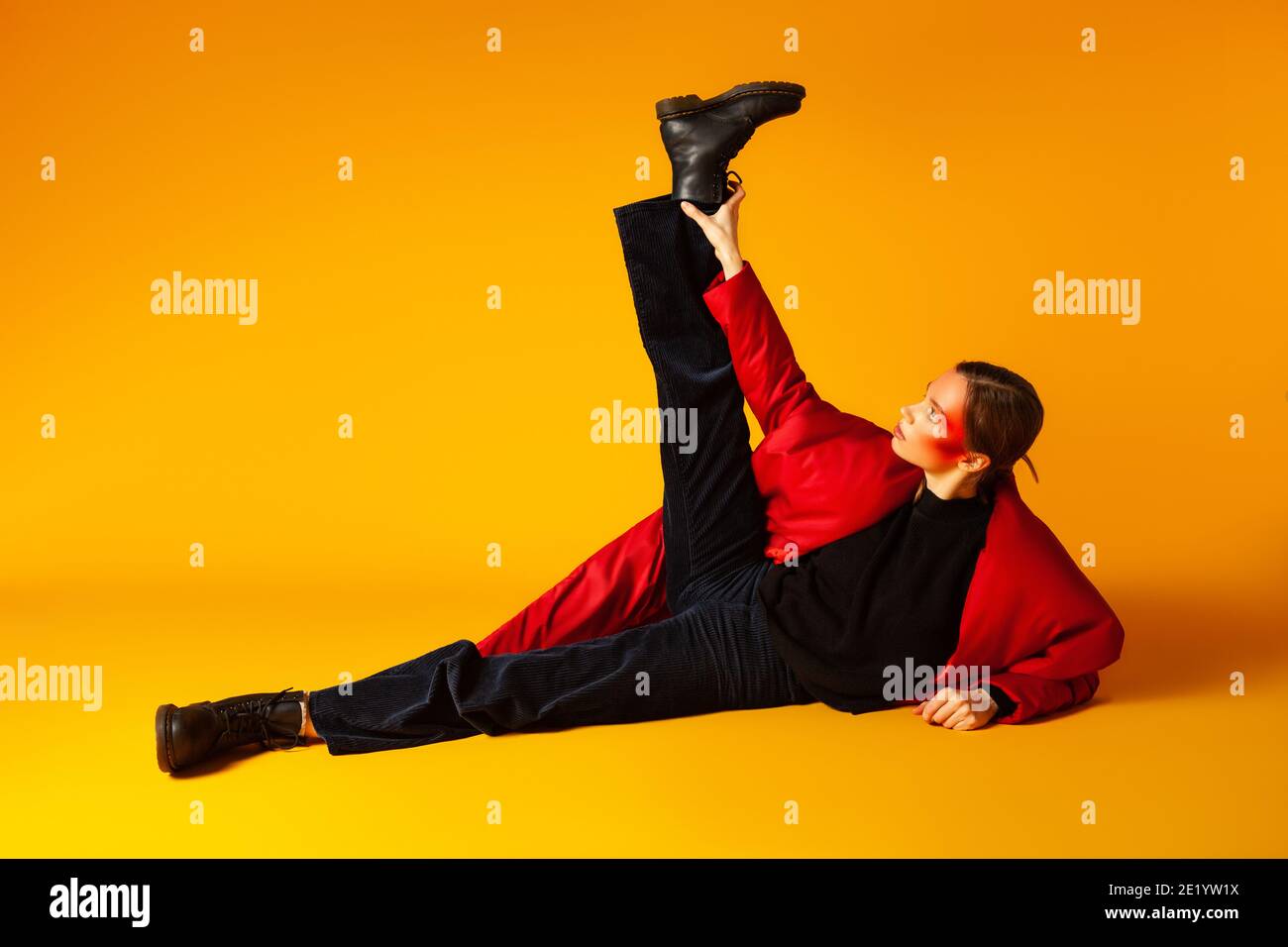 Stylish female model stretching on yellow background Stock Photo - Alamy