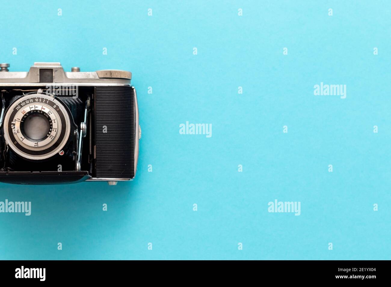 Old retro camera seen from top view in flat lay against blue pastel ...