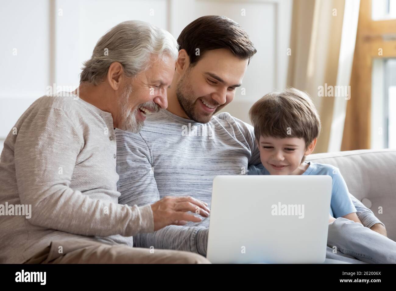 Smiling three generations of men use laptop together Stock Photo - Alamy