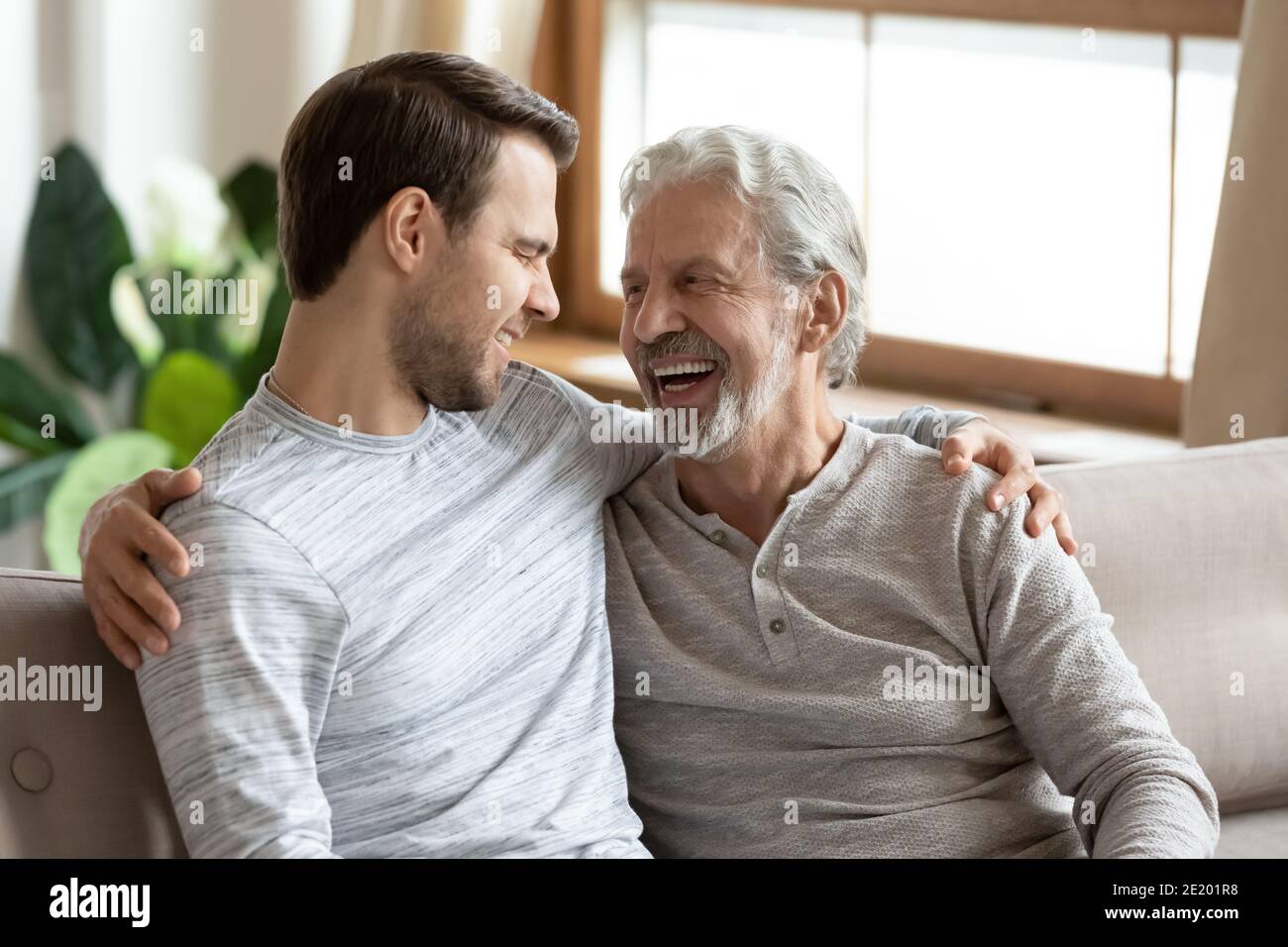 Smiling mature dad and grownup son relax together at home Stock Photo ...
