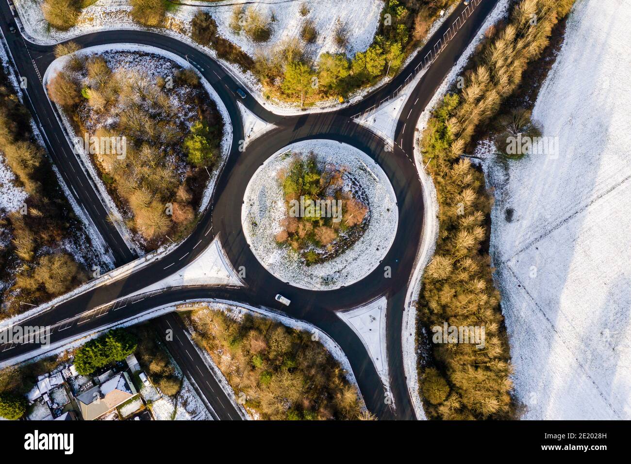 Aerial view of a traffic roundabout surrounded by snow and trees in a ...