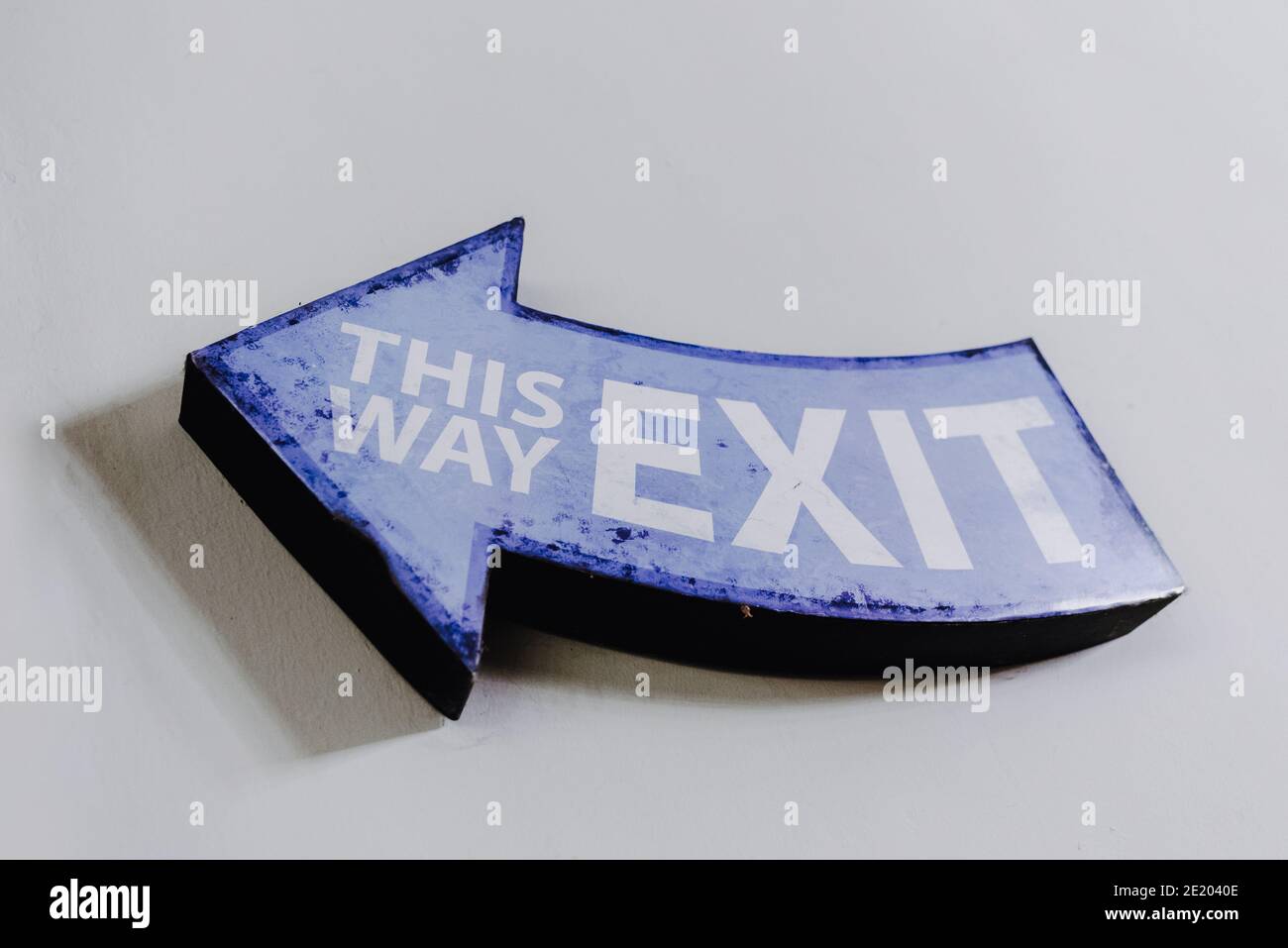 This Way Exit written on a decorative blue wooden arrow hanging on a ...