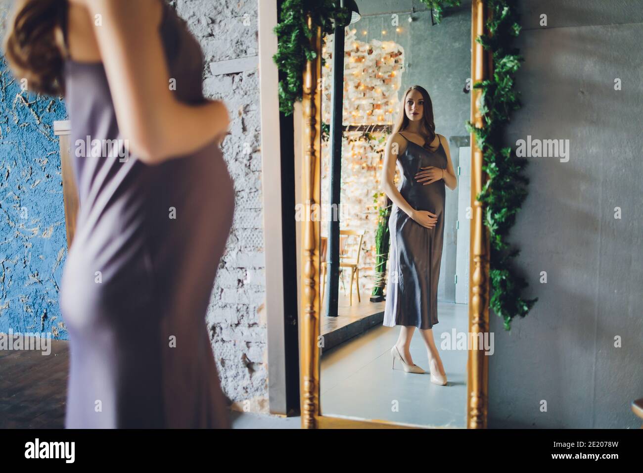 A happy pregnant woman looks lovingly at a reflection of herself and ...