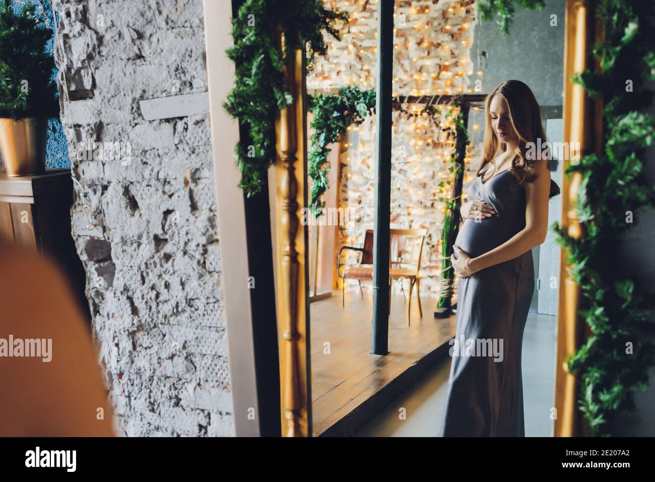 A happy pregnant woman looks lovingly at a reflection of herself and ...