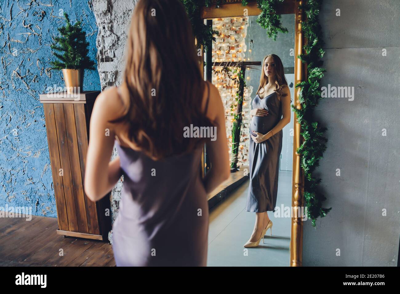 A happy pregnant woman looks lovingly at a reflection of herself and ...