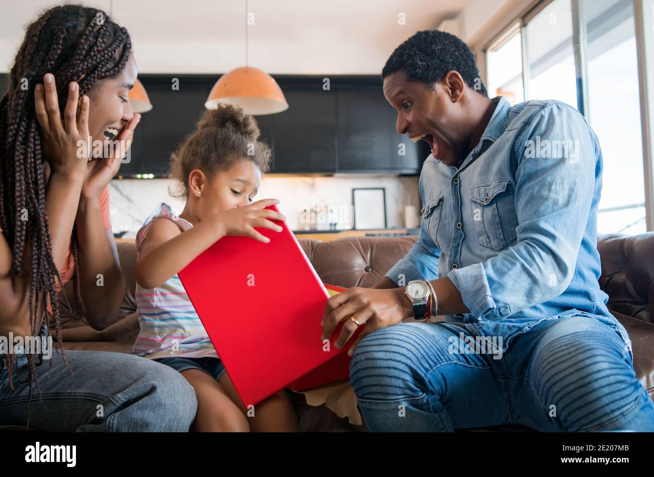 Little girl receiving gift from her parents Stock Photo - Alamy