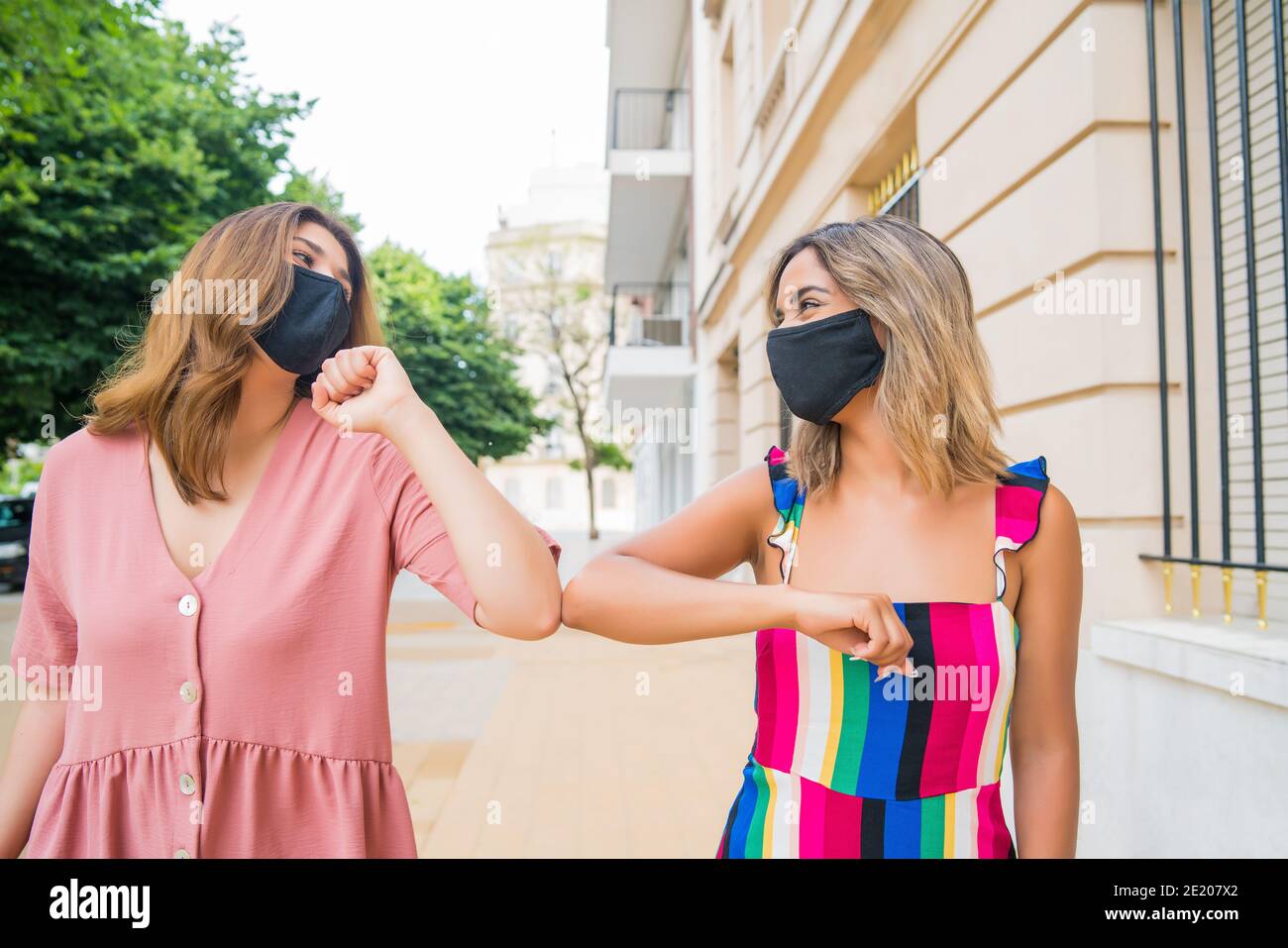 Two friends bumping elbows outdoors Stock Photo - Alamy