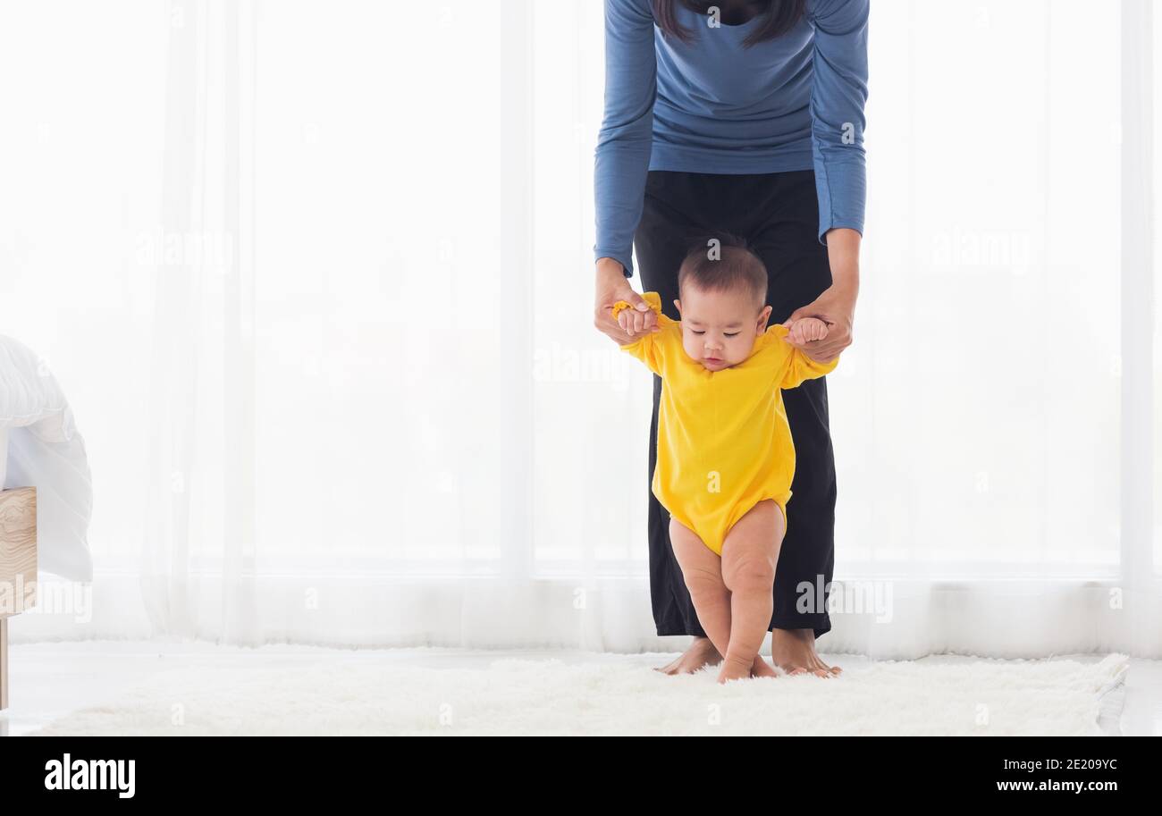 Asian little baby girl taking first steps learning to walk with mom ...