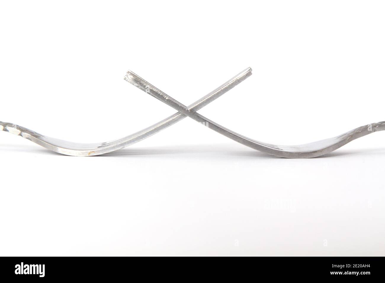 Closeup of the crossed tines of two forks. White background, selective ...