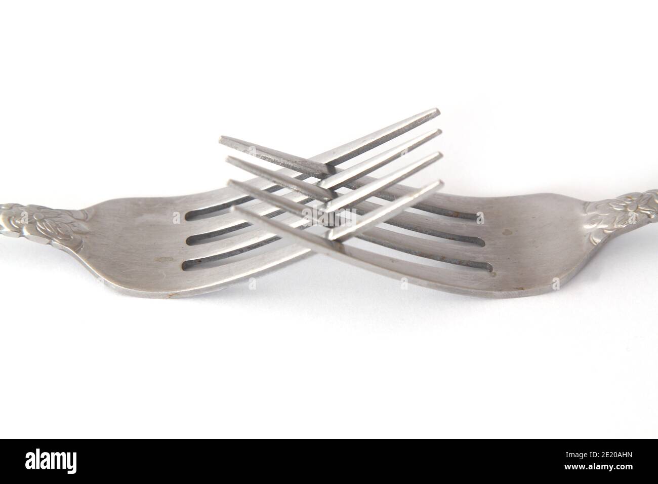 Closeup of the crossed tines of two forks. White background, selective ...
