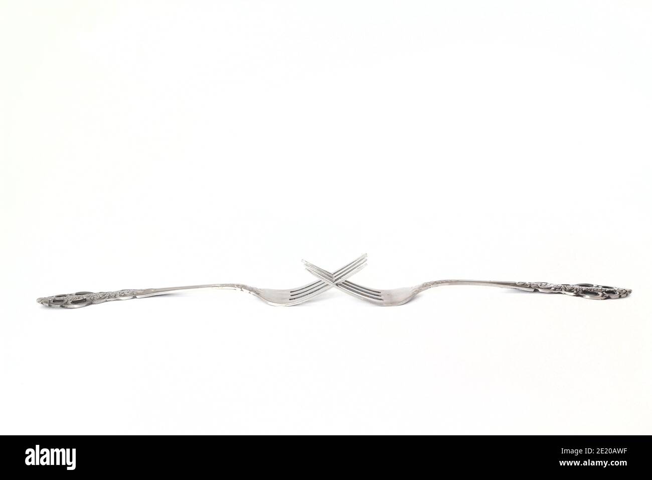 Closeup of the crossed tines of two forks. White background, selective ...