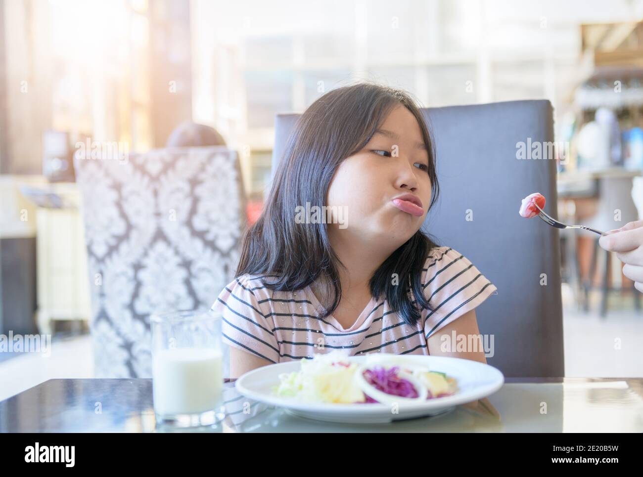 asian child girl with expression of disgust against tomato in salad ...