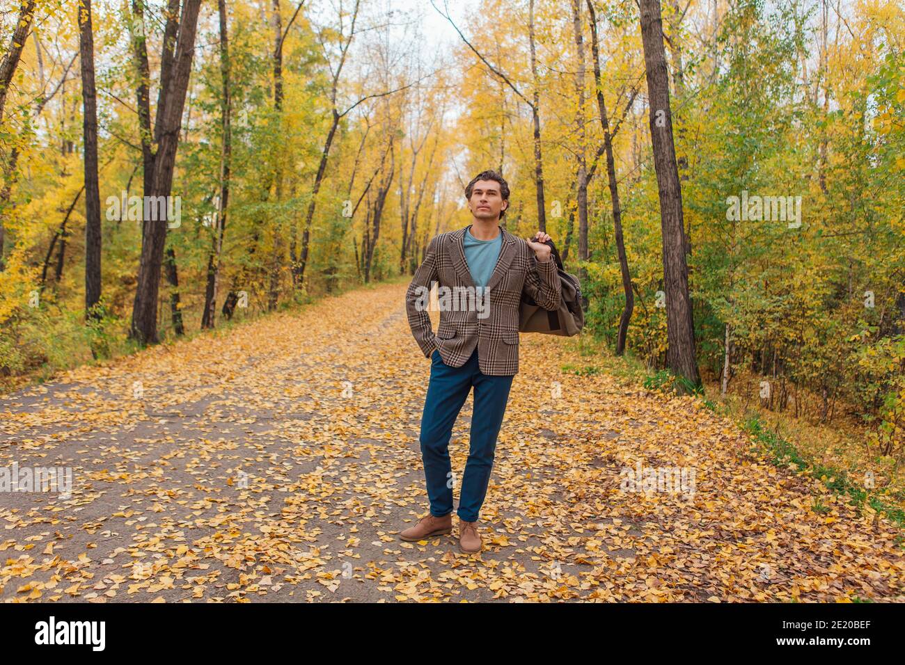 Tall handsome man with a bag on the autumn alley Stock Photo - Alamy