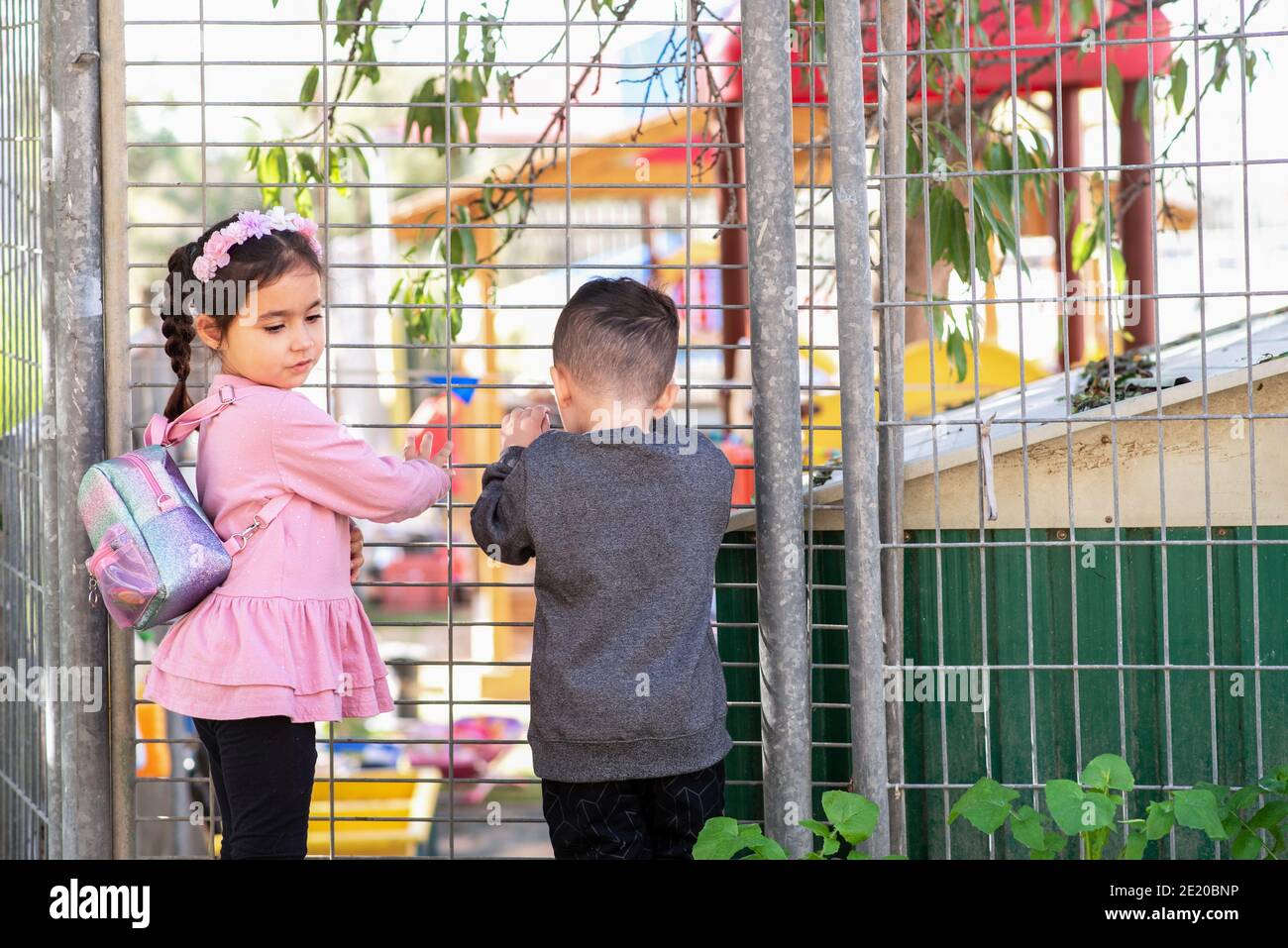 Children near the gate of closed preschool. Little kids outside school ...
