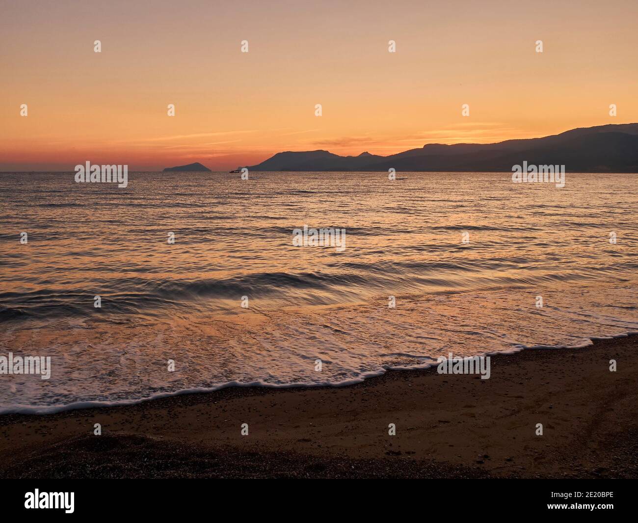 Sunset landscape with sea and mountains at the horizon. Sea coast in ...