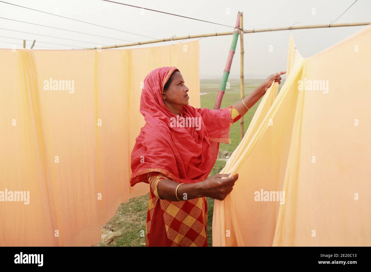 A woman collects dry fabric after a dyeing process at a factory in ...
