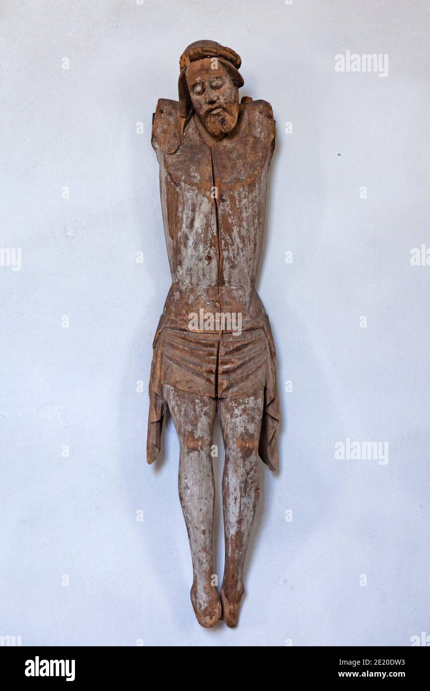 very old Jesus figure in wood mounted on church wall, arms missing ...