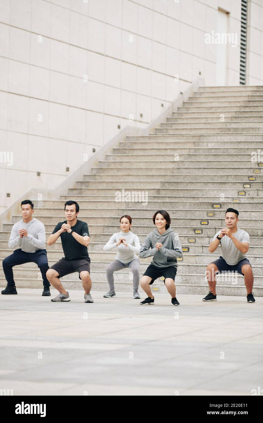Fit people doing squats outdoors Stock Photo - Alamy