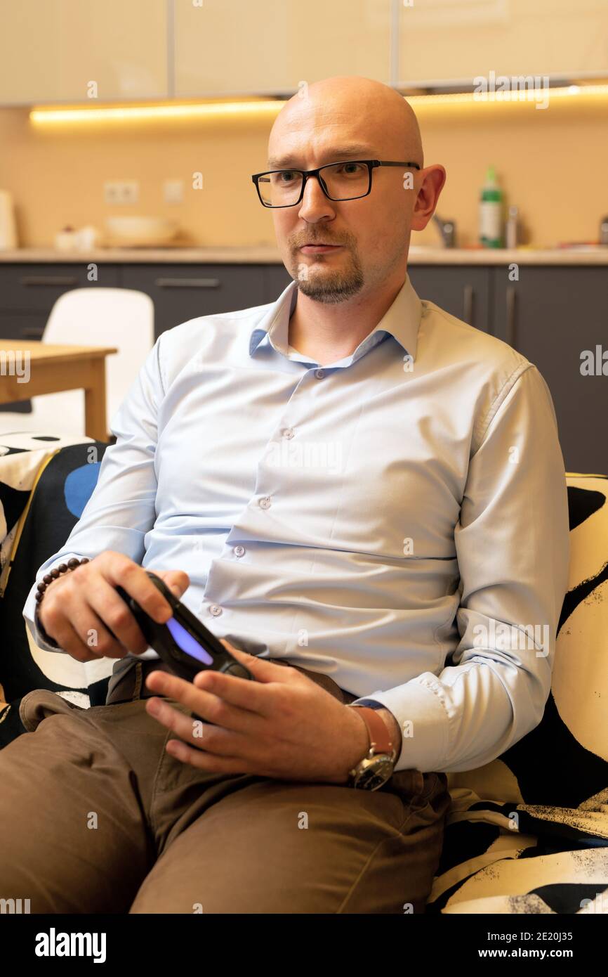 Concentrated middle age man playing video games with joystick at home ...
