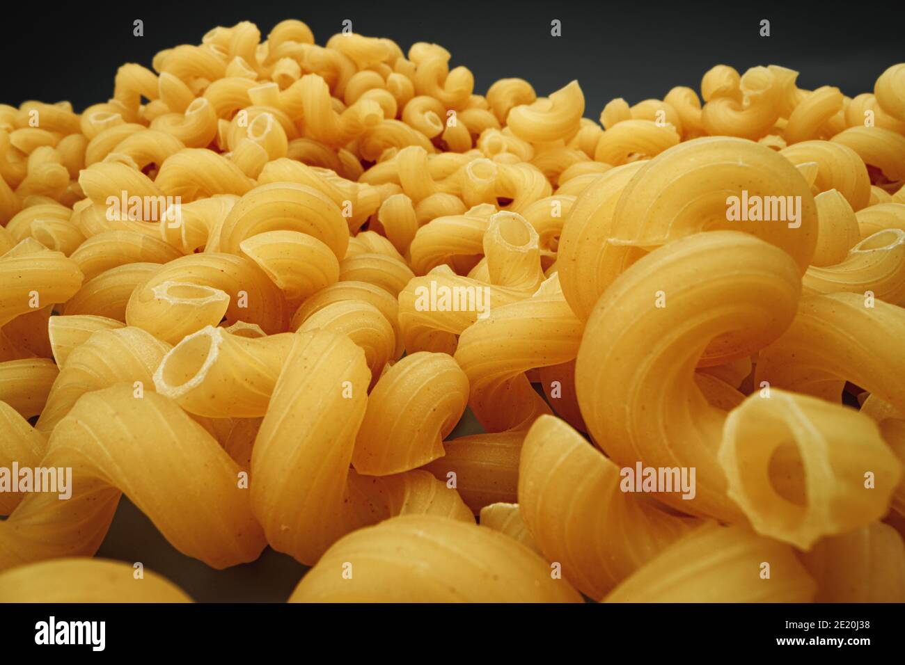 Uncooked pasta swirls on dark background macro Stock Photo - Alamy
