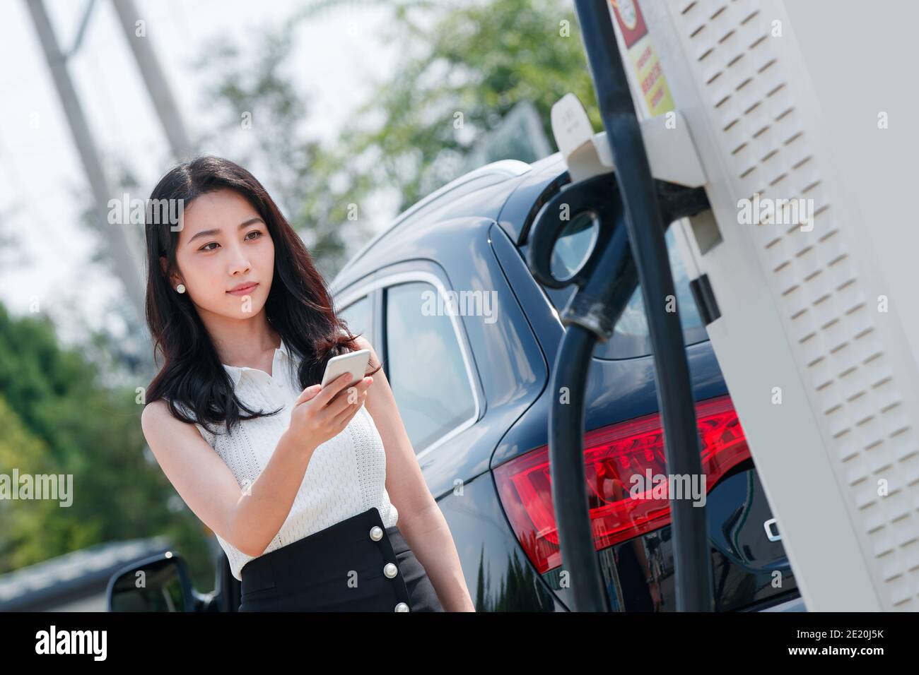 Young women use a mobile phone charging car buffet Stock Photo - Alamy