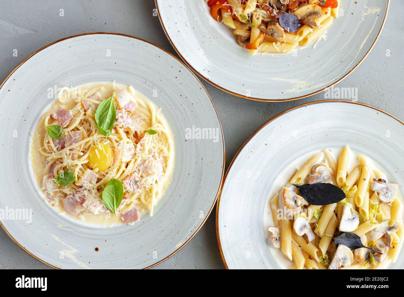 Three types of pasta served on grey table Stock Photo - Alamy