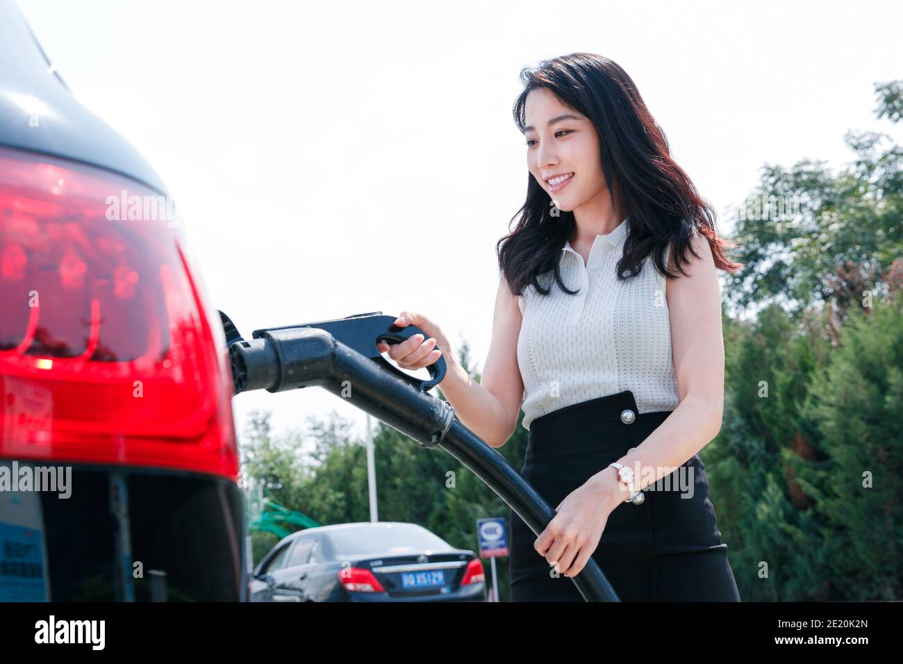 A beautiful young woman to car battery Stock Photo - Alamy