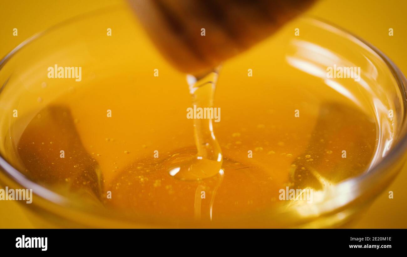 Close up of golden honey. Flow of honey. honey dipper is inside Yellow ...