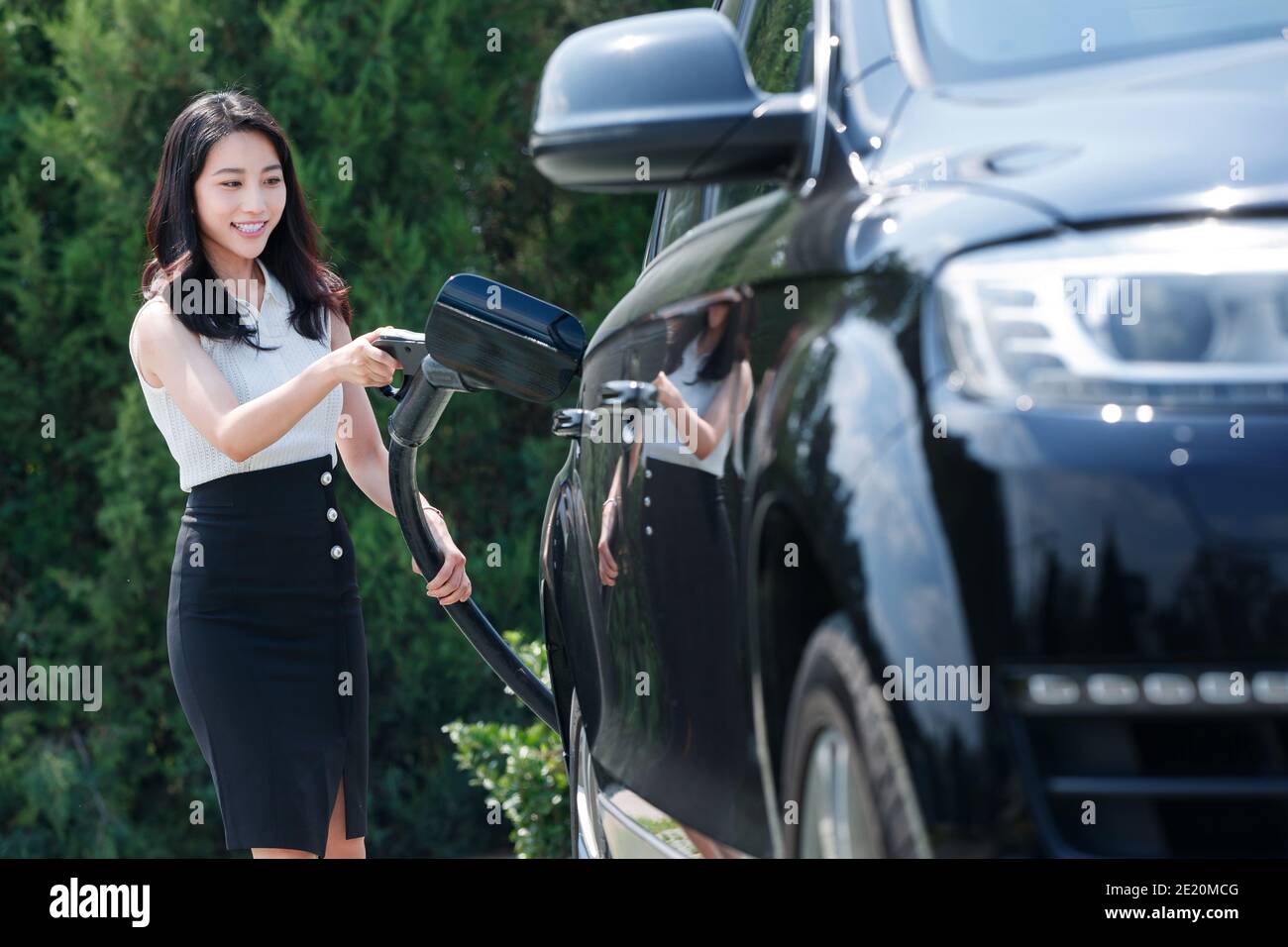 A beautiful young woman to car battery Stock Photo - Alamy