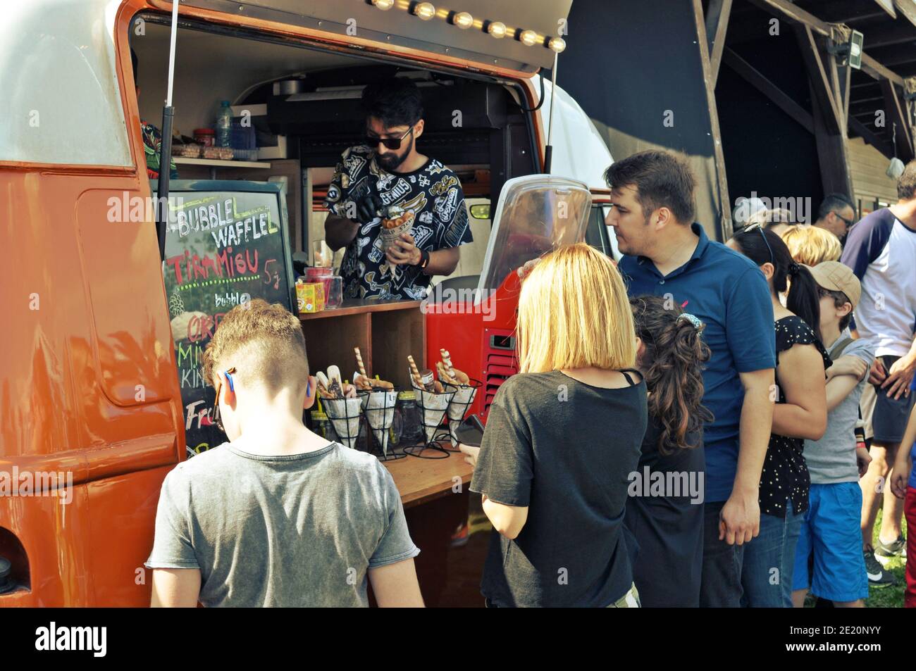 People standing in line in front of an auto stall at burger festival ...