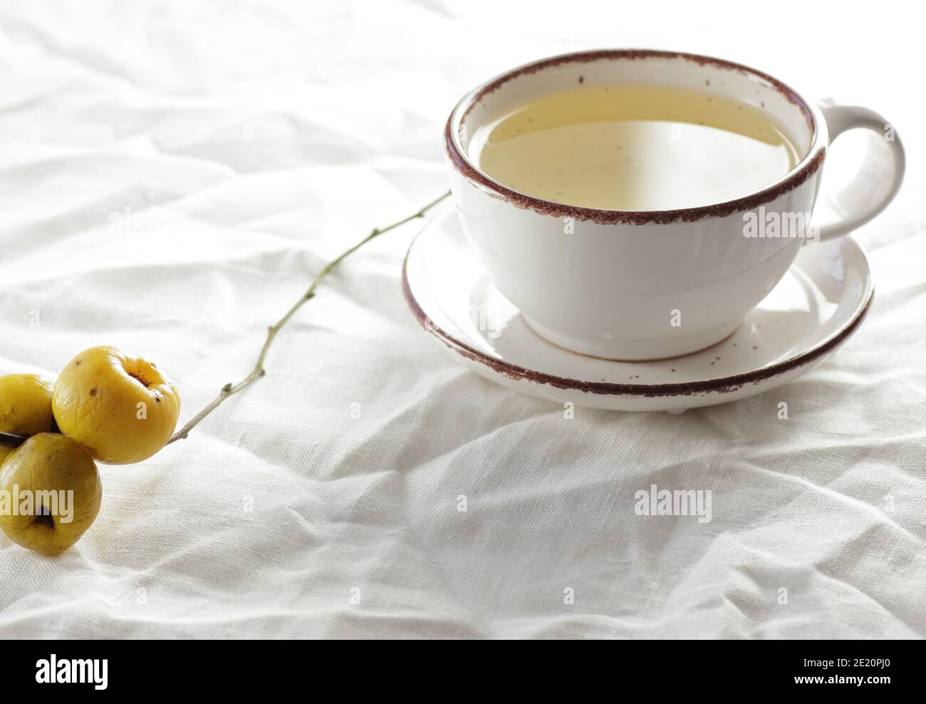 Green tea with japanese quince on white linen textile, minimalist ...
