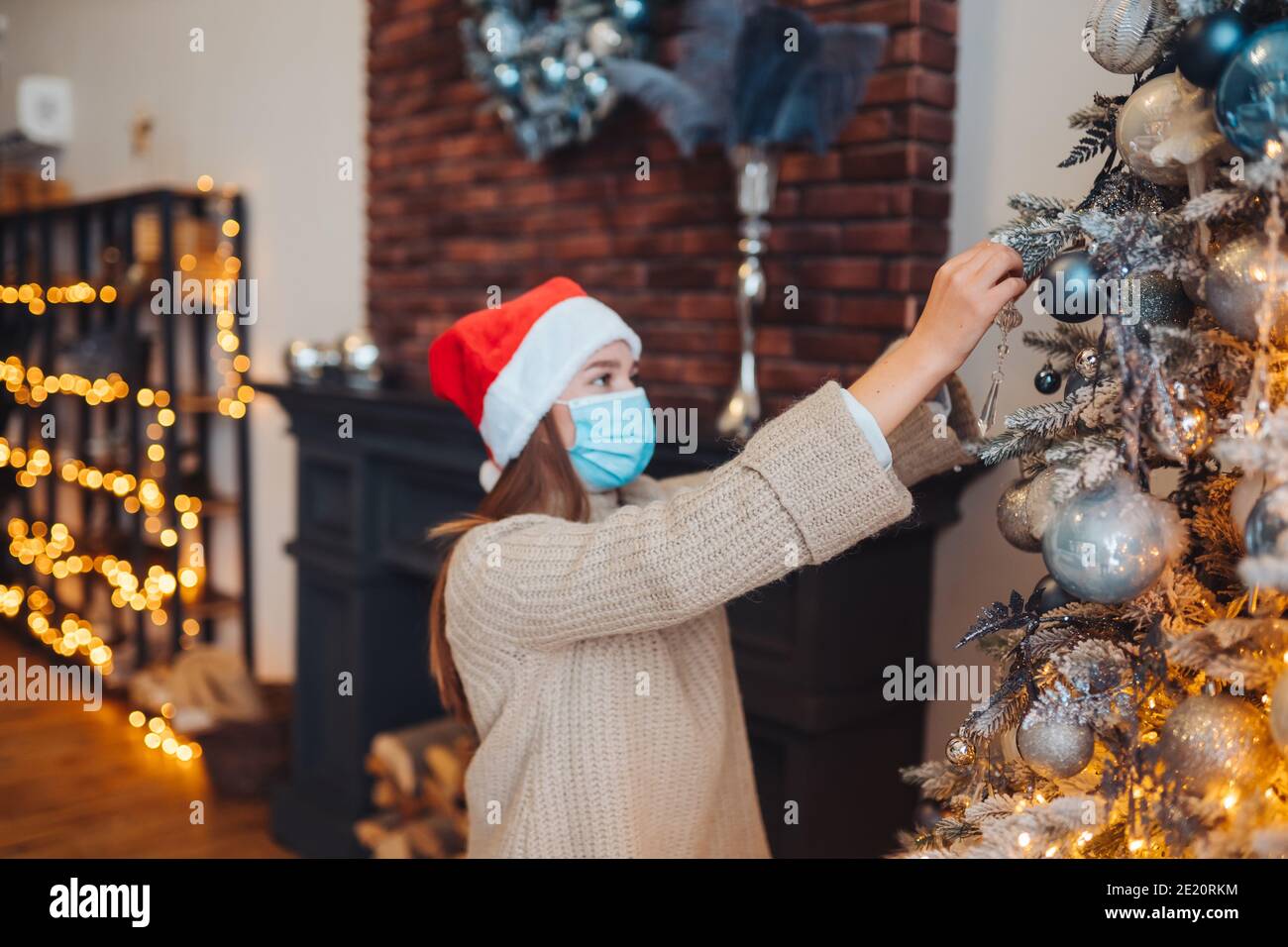 A young woman decorates the Christmas tree in medical masks Stock Photo ...