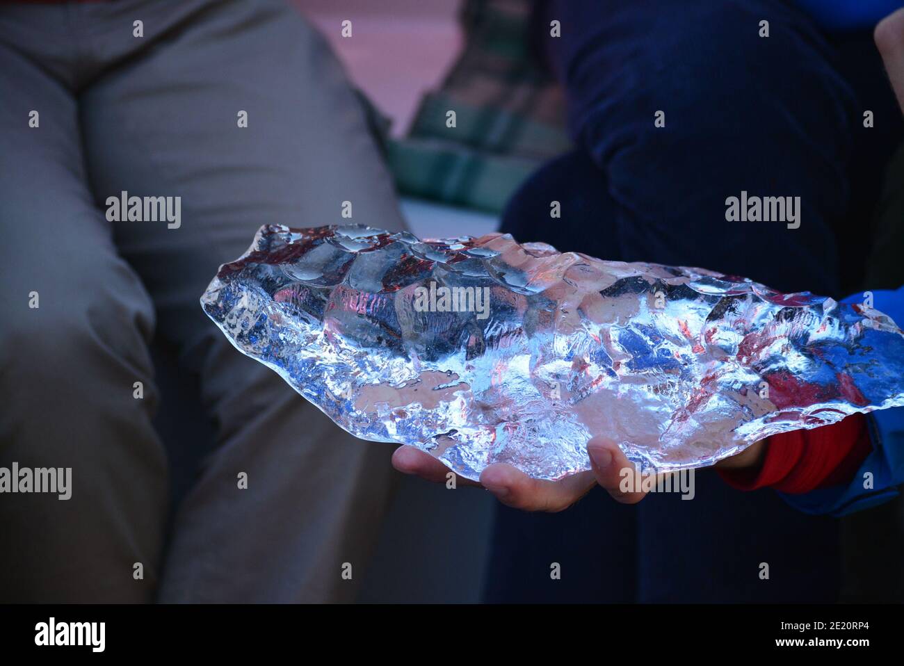 carved black ice holding in a hand, Ilulissat icefjord in the midnight ...