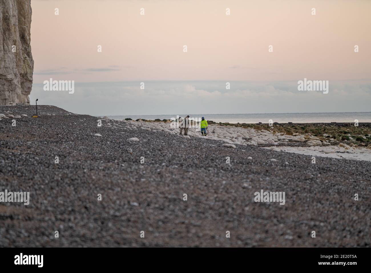 Coastguasrd and MoD bomb disposal offcier look at an unexploded shell ...
