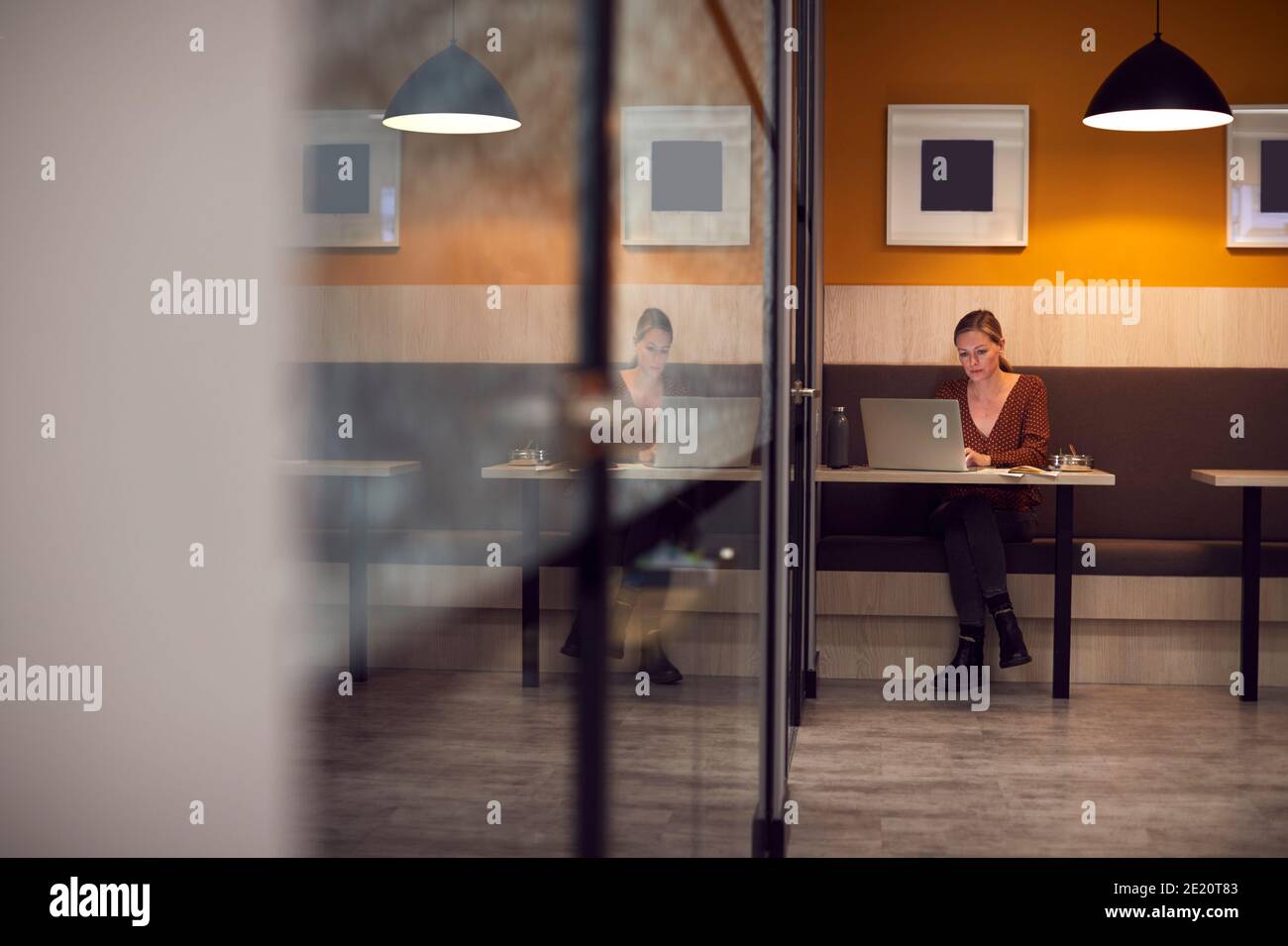 Businesswoman Working Late In Open Plan Office Using Laptop Stock Photo ...