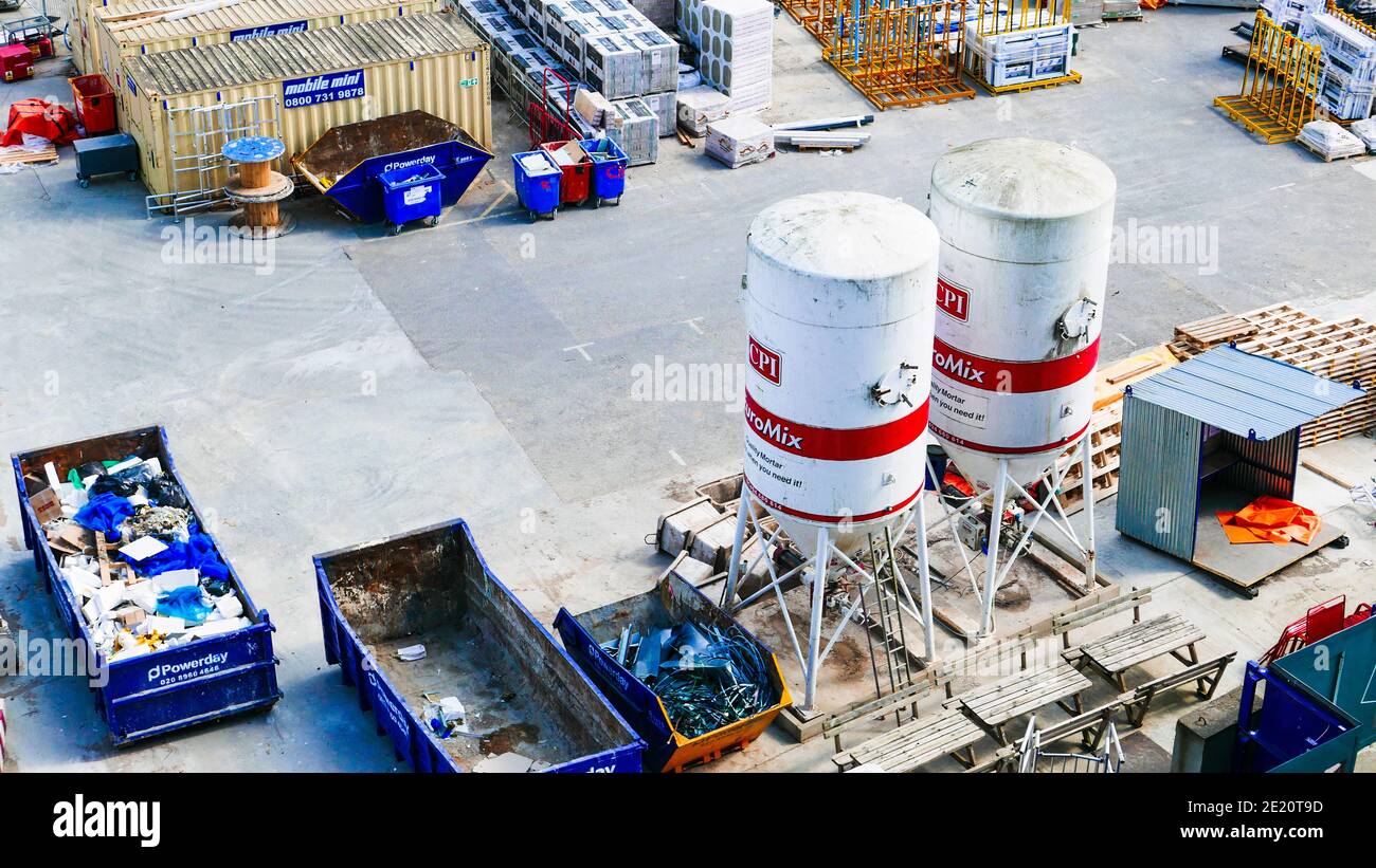 Builders construction yard site with two Euromix mortar silos, skips ...