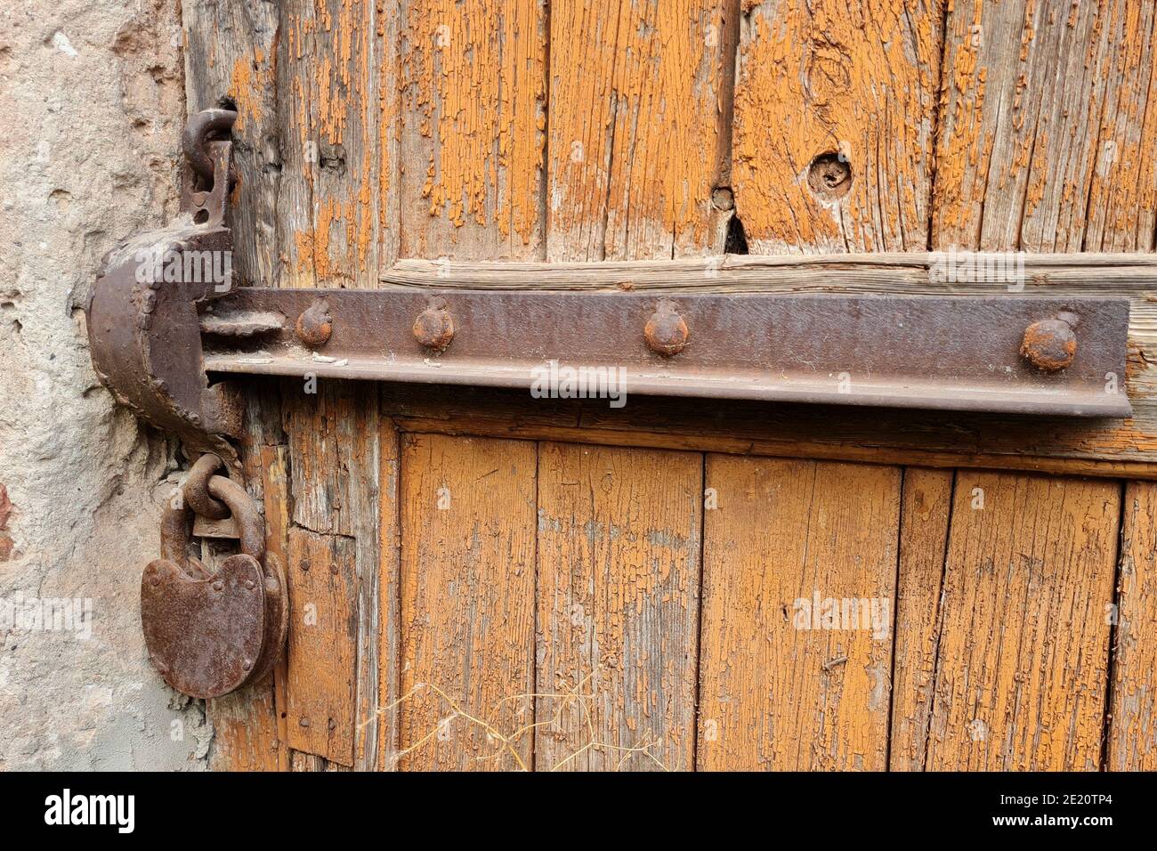 Rusty iron lock on a old wooden door with a peeled yellow paint ...