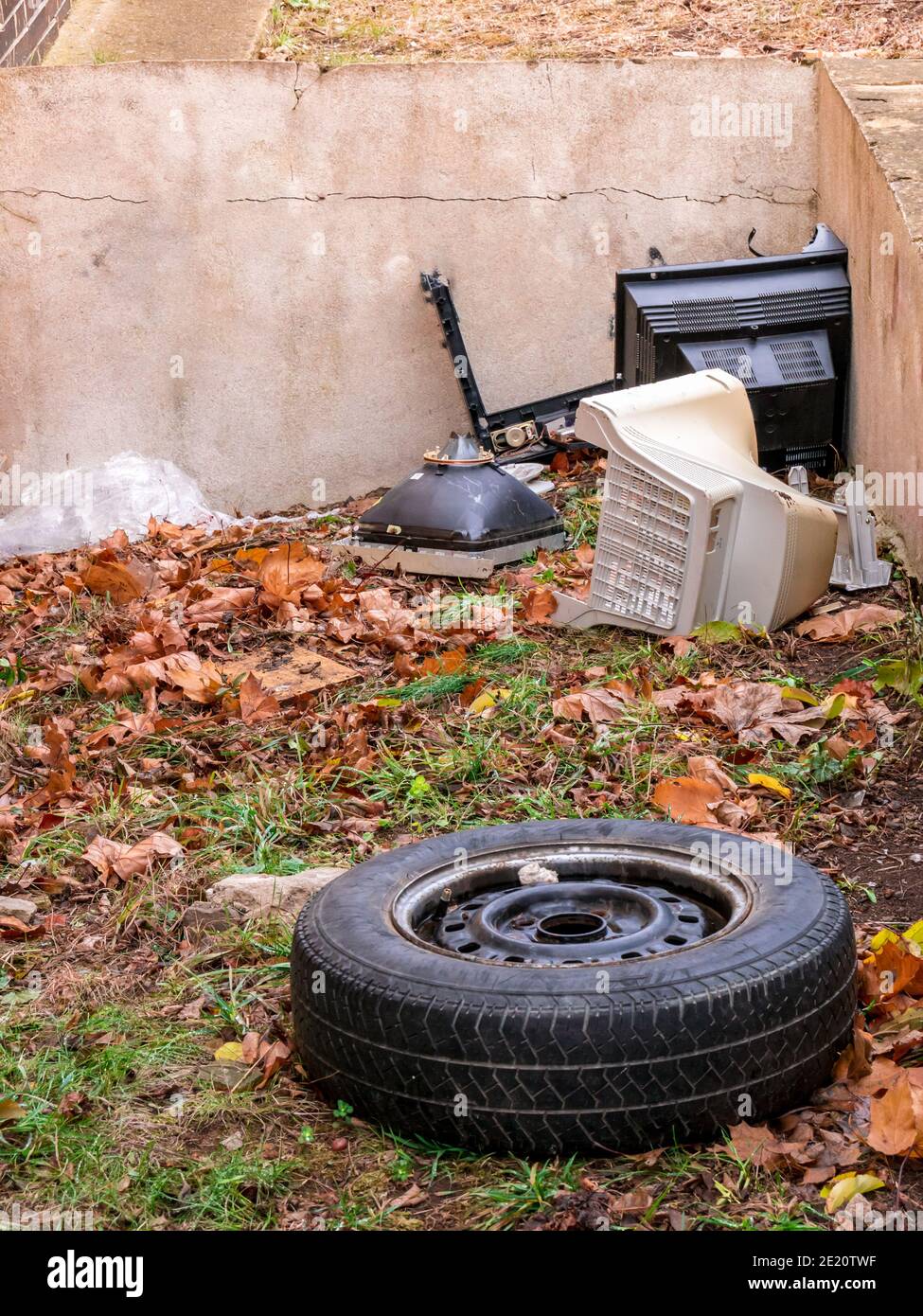 Old tire, CRT computer and TV monitors smashed to pieces in dark corner ...