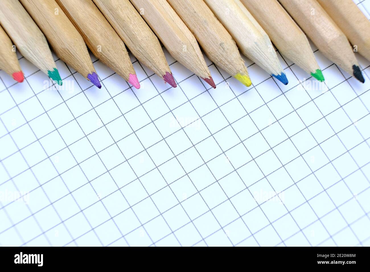 Closeup set of multicolored pencils on the checkered paper sheet of ...