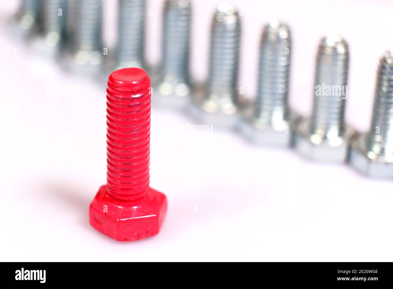 Close-up of pink bolt n a group of galvanized metallic screws ...