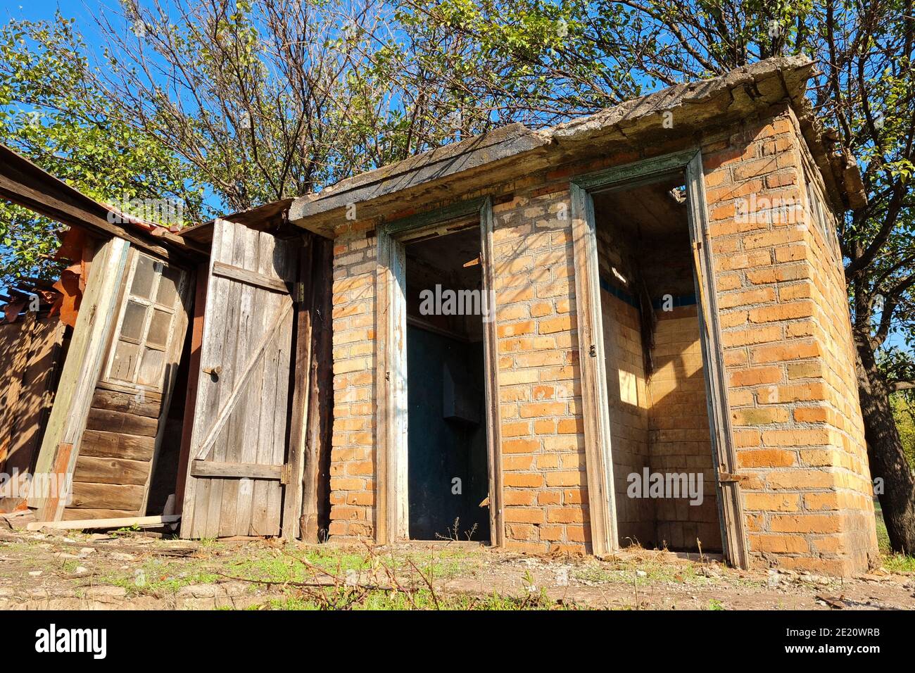 abandoned old brick toilet with two doors at sunny summer day outdoors ...