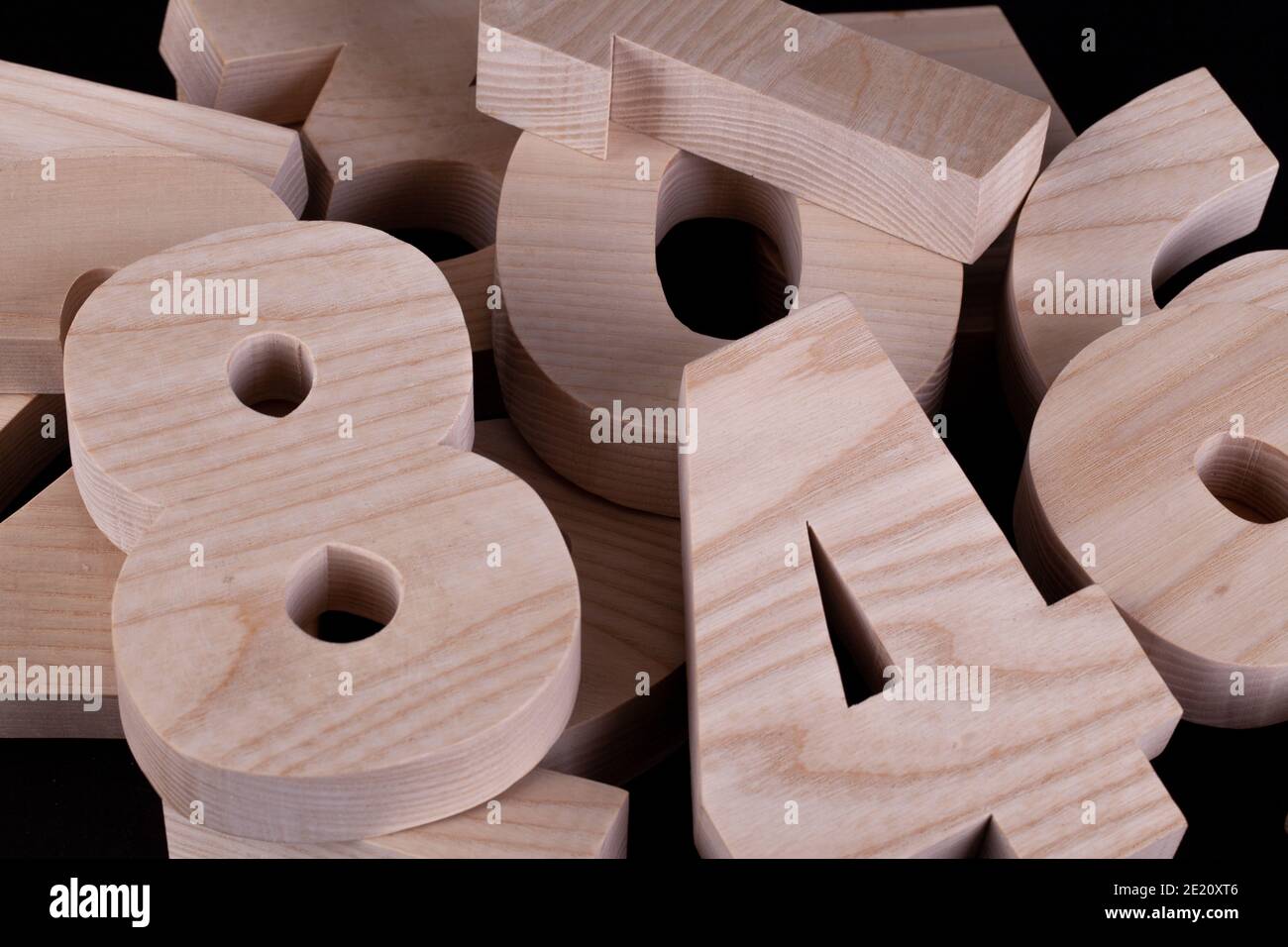 Large random wooden numbers laying in a pile close up with a black ...