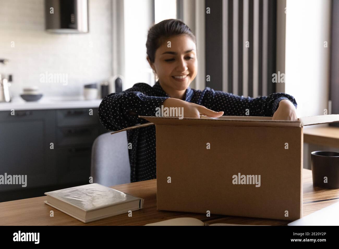 Smiling Indian woman unpack box with internet order Stock Photo - Alamy
