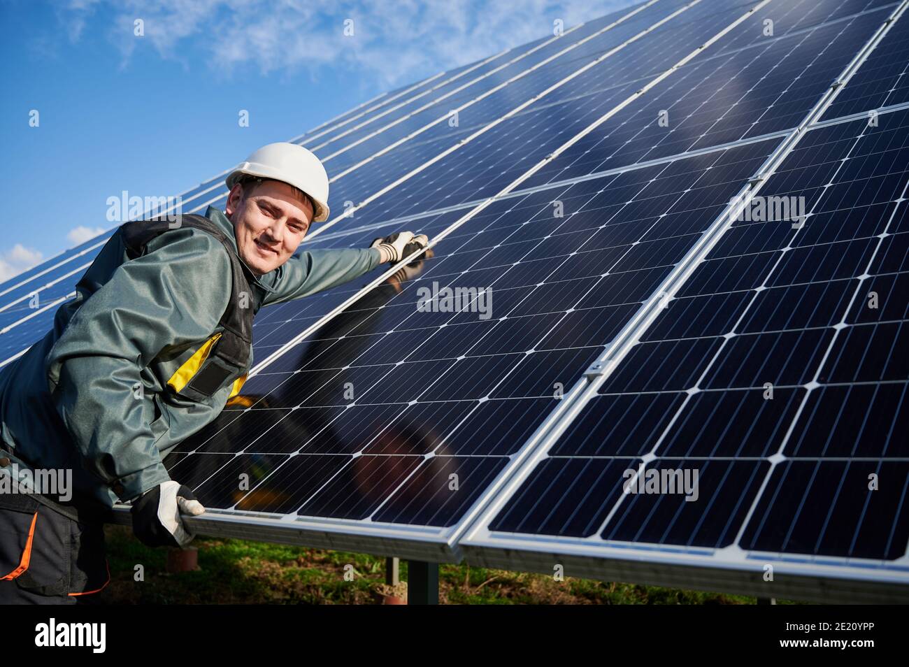 Joyful man electrician in safety helmet repairing photovoltaic solar ...