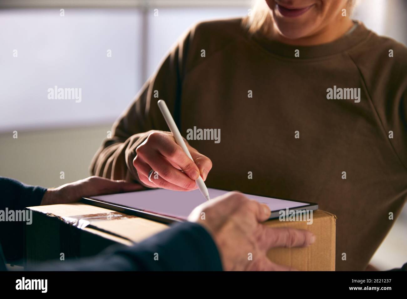 Woman Signing For Courier Delivery To Office Using Digital Tablet Stock ...