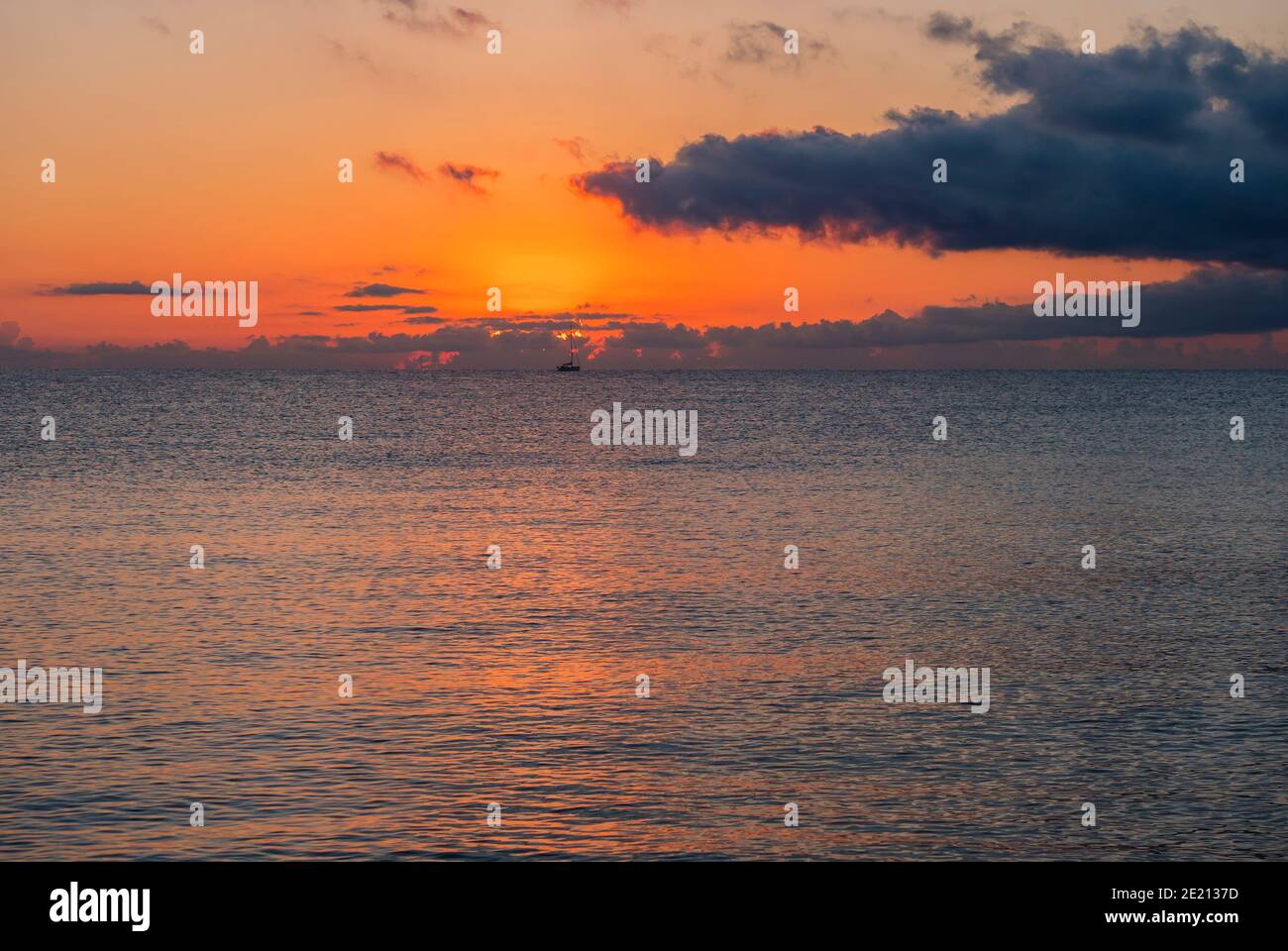 Sunrise with the red orange sun raising up from the sea with dark ...
