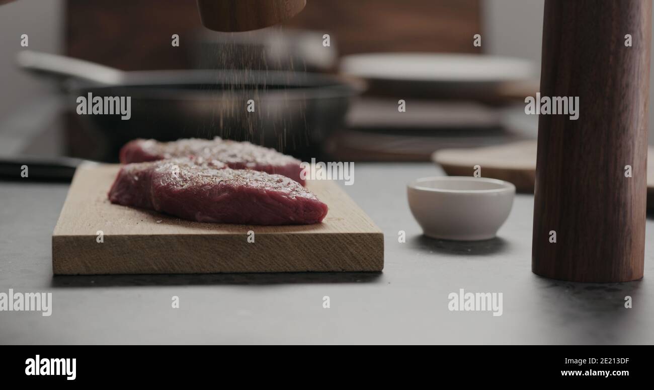man grinding pepper on raw beef steak on oak board, wide photo Stock ...