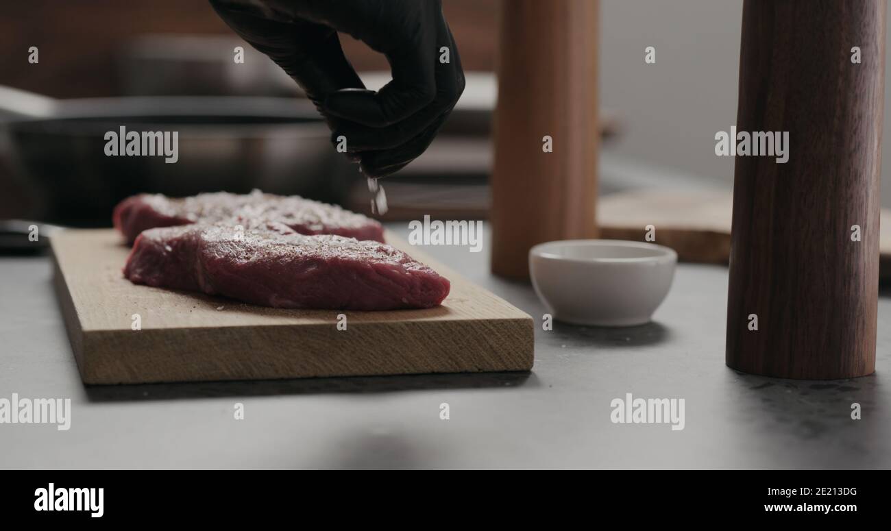 man salting raw beef steak on oak board, wide photo Stock Photo - Alamy